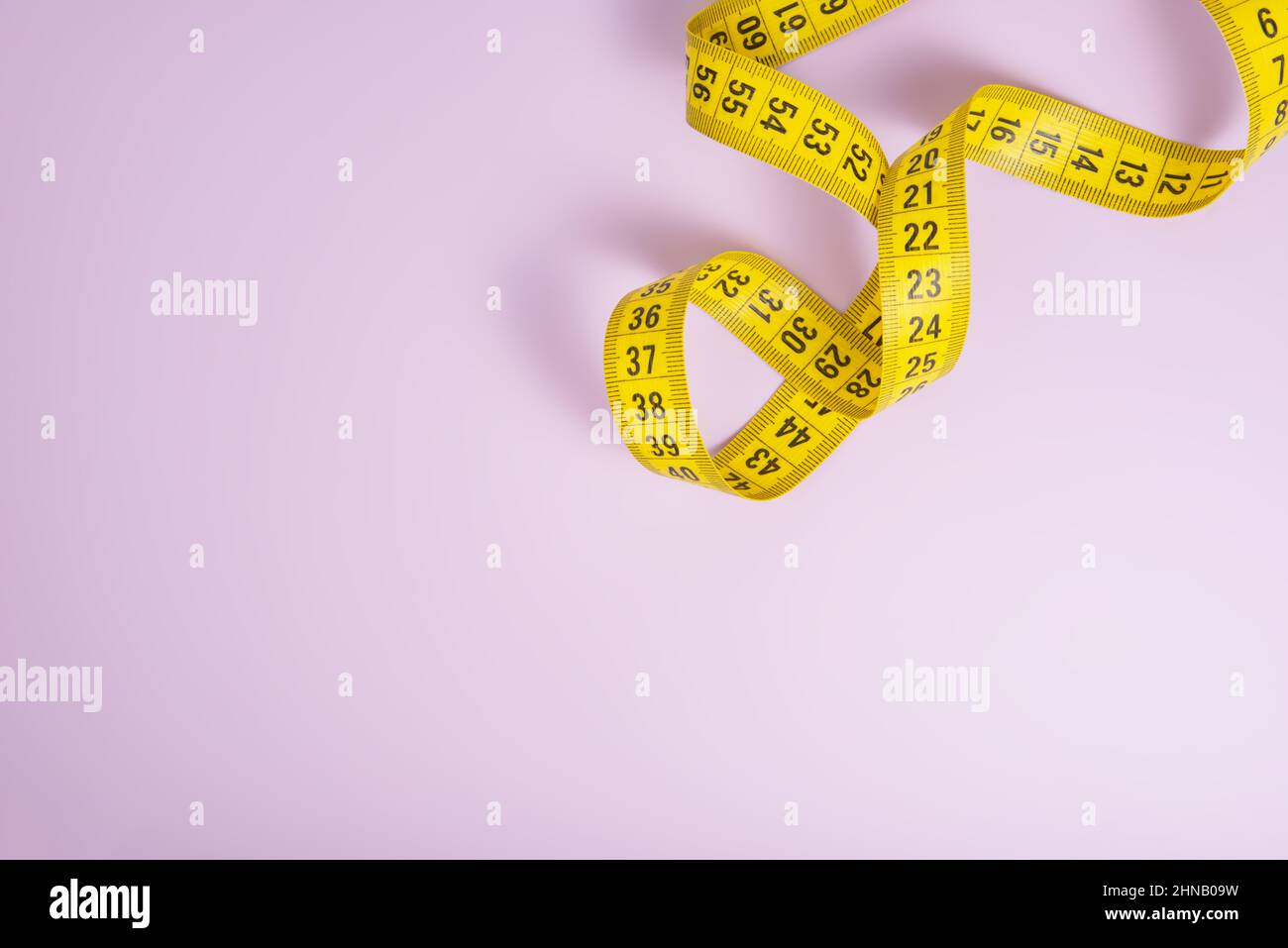 Yellow spiral tape measure on violet background with copyspace Stock ...