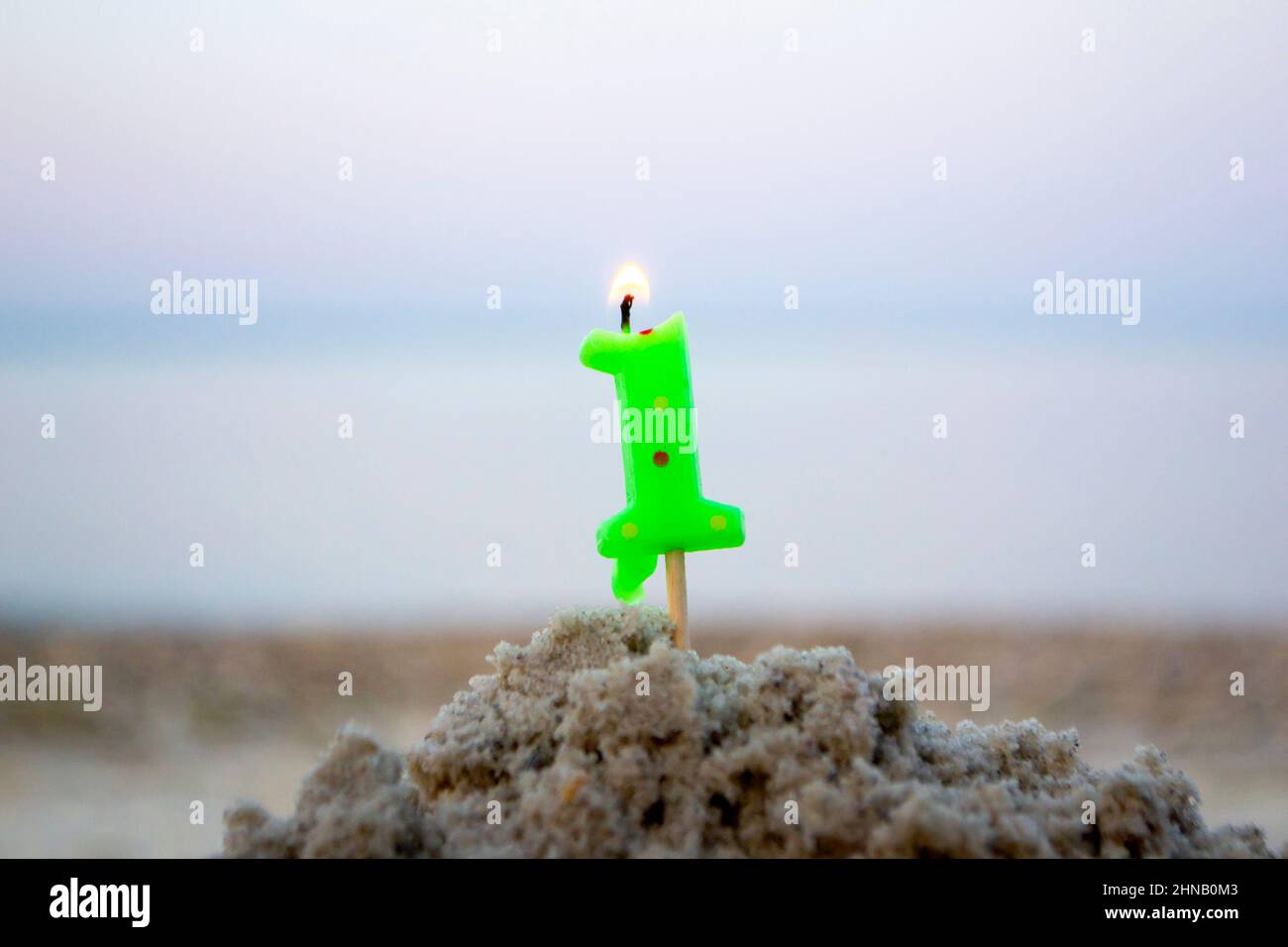 Candle number one on stick inserted into sand and burns. Lighted candle ...