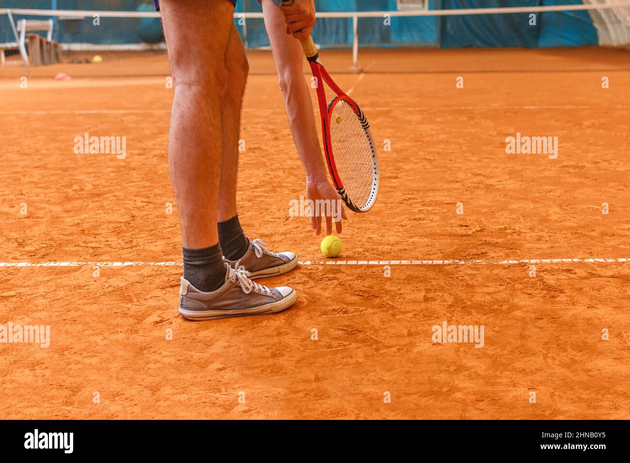 Tennis player holding racket and pick up yellow ball ready to serve ...