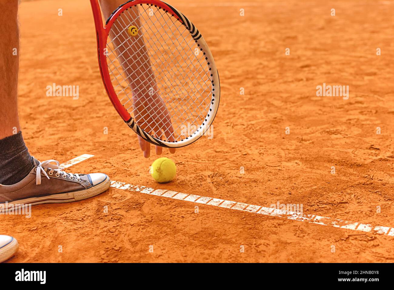 Tennis player holding racket and pick up yellow ball ready to serve on ...