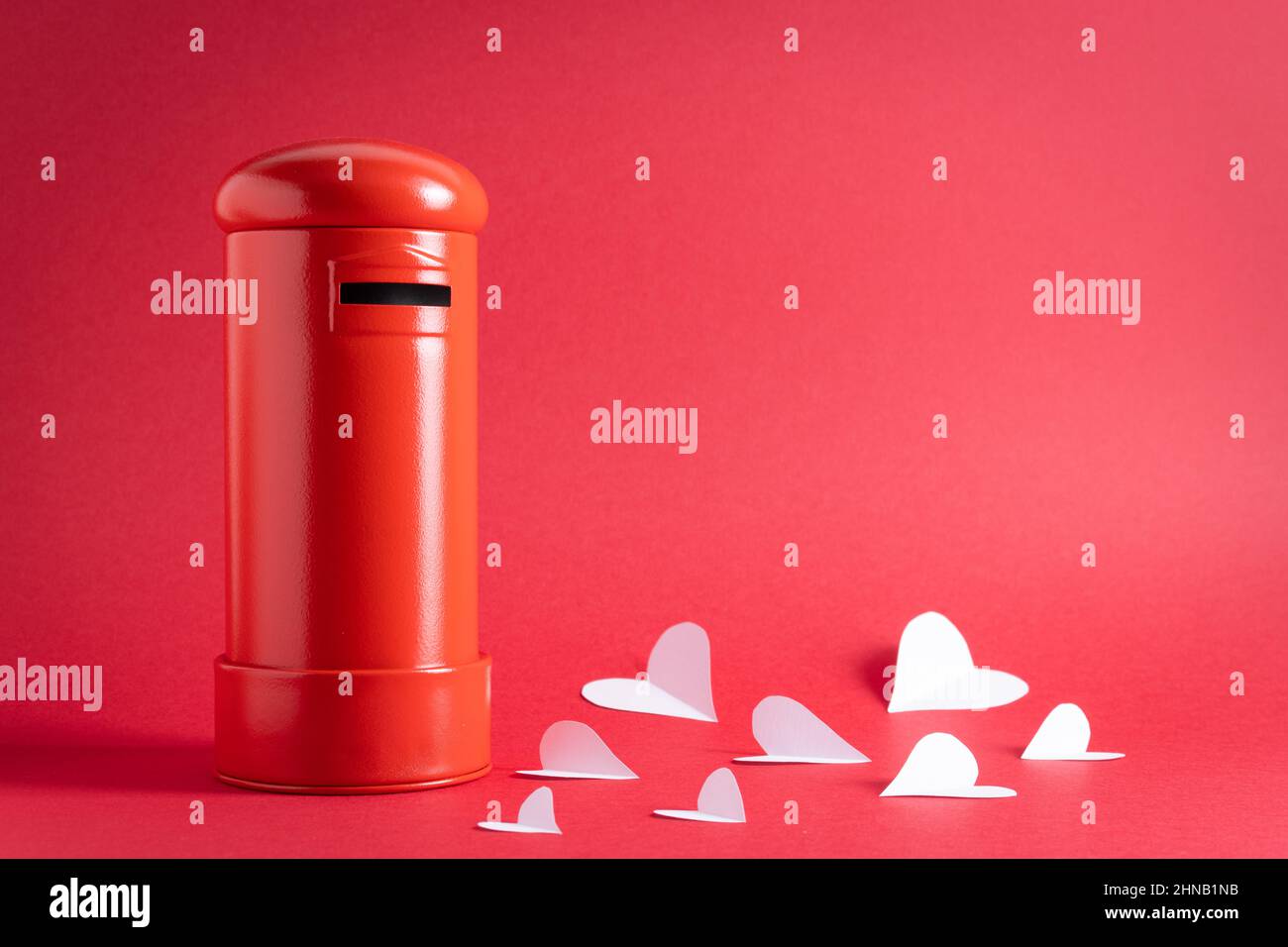Closeup of a red mailbox and white paper hearts on a red background for ...