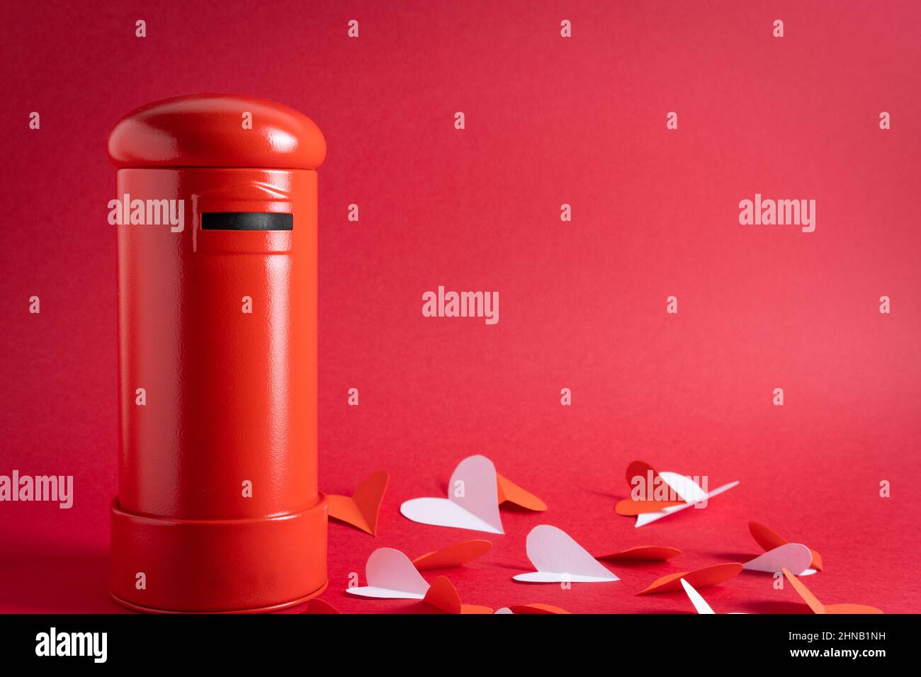 Closeup of a red mailbox and white paper hearts on a red background for ...
