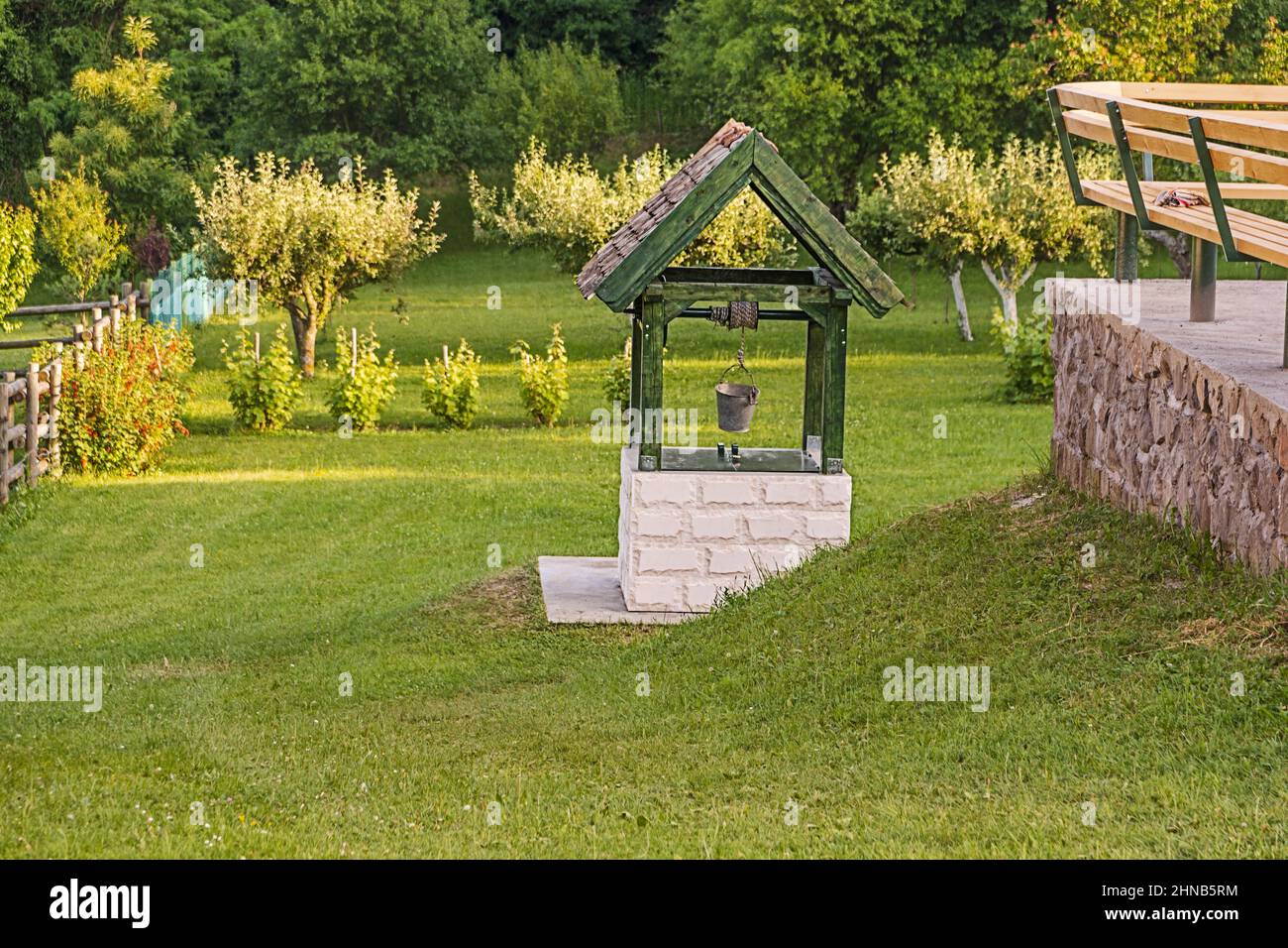 Water stone well on country with green grass and forest background ...