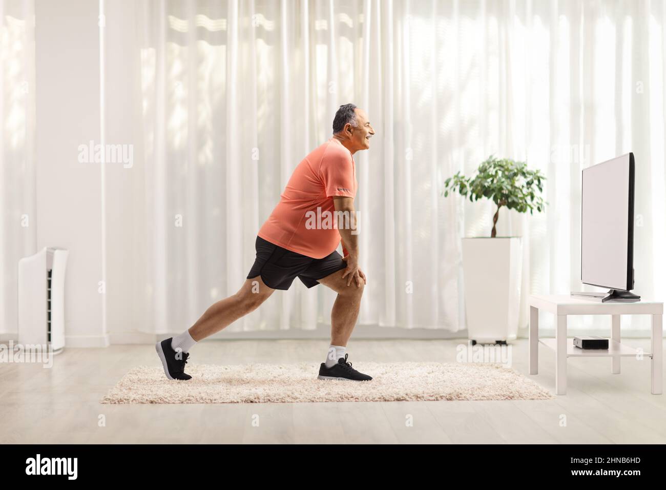 Full length profile shot of a mature man stretching his leg in front of ...