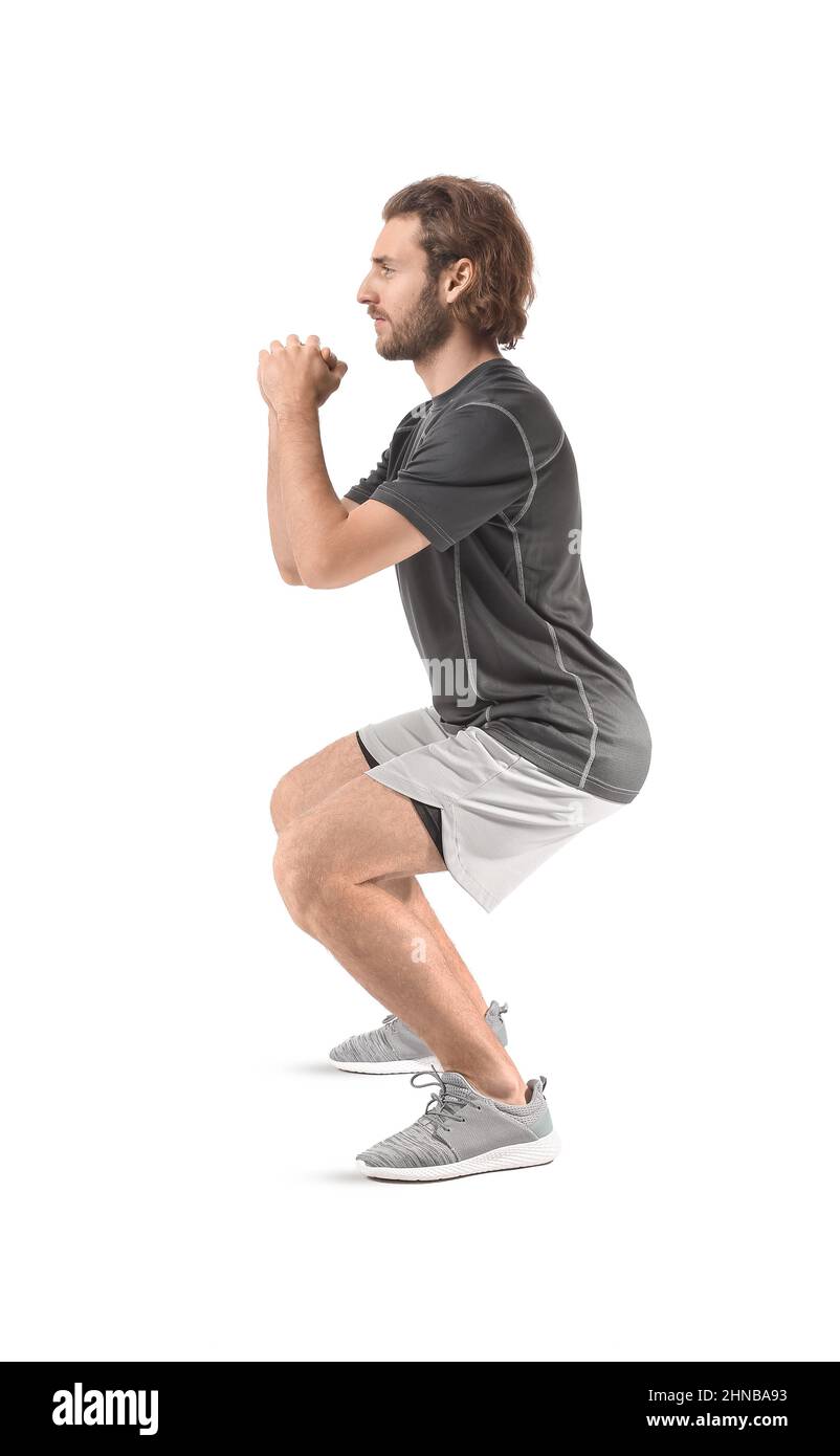 Sporty man doing squats on white background Stock Photo - Alamy