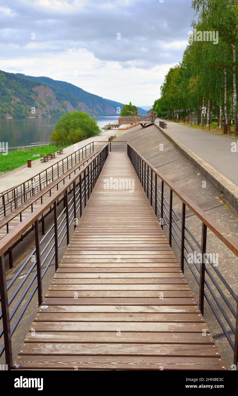 Wooden ramp on the bank of the big Siberian river with rocky shores ...