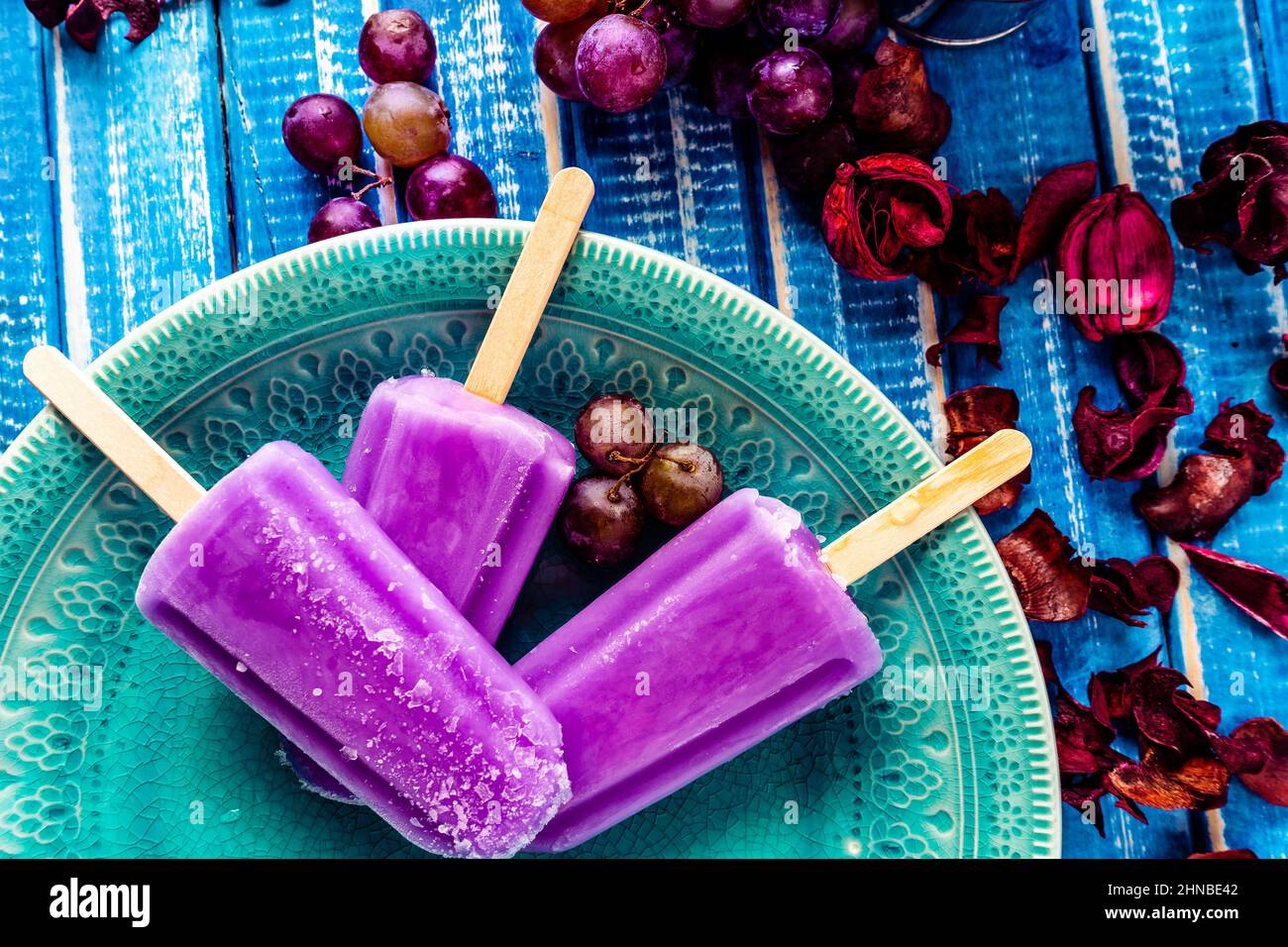 Lollipop style grape ice cream on a stick on a vintage plate on a light ...