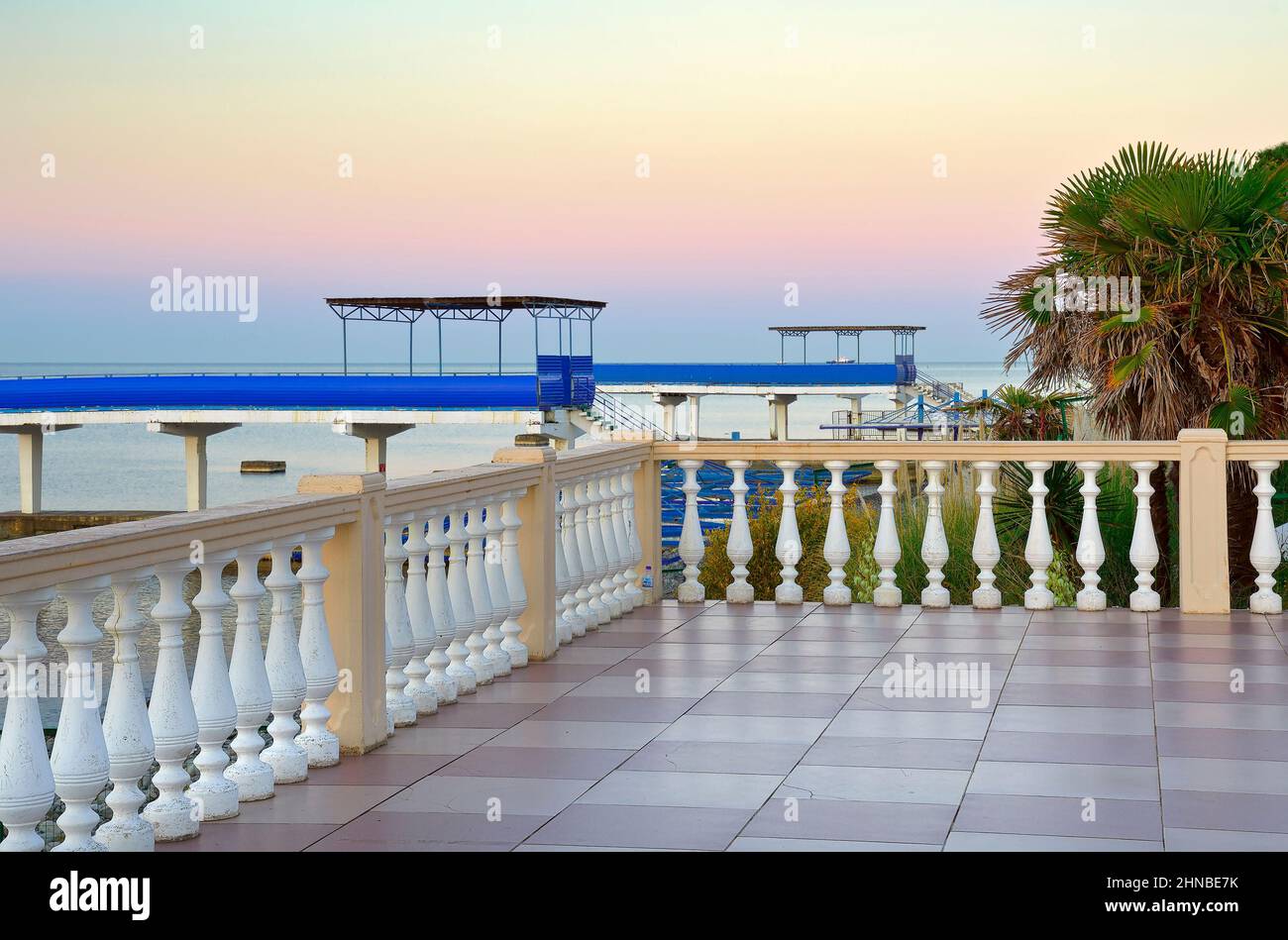 The platform at the beach pier above the water against the blue-pink ...