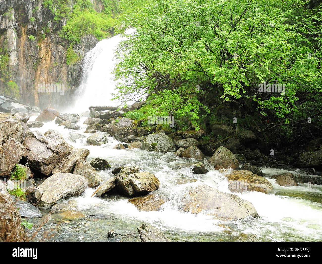 A powerful stream of a large waterfall flows down from the mountain ...