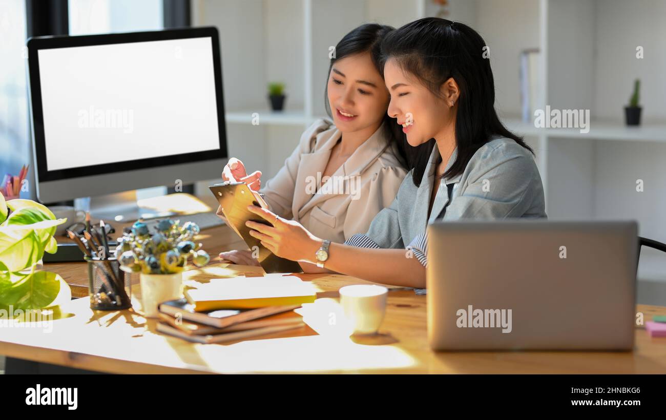 Two Asian female coworkers work together help cooperate on project in ...