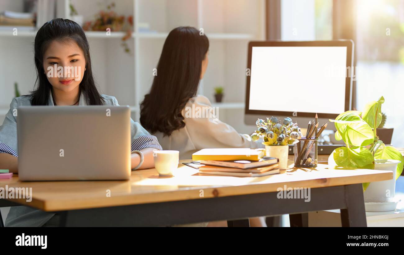 Two concentrated businesswomen are working on their computer at their ...