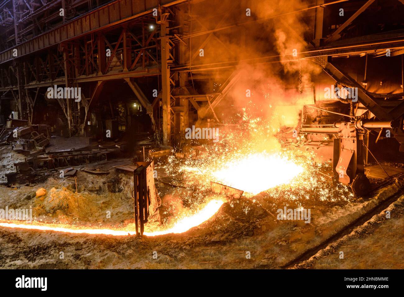 The flow of molten hot metal, molten steel flows along the guide chute ...
