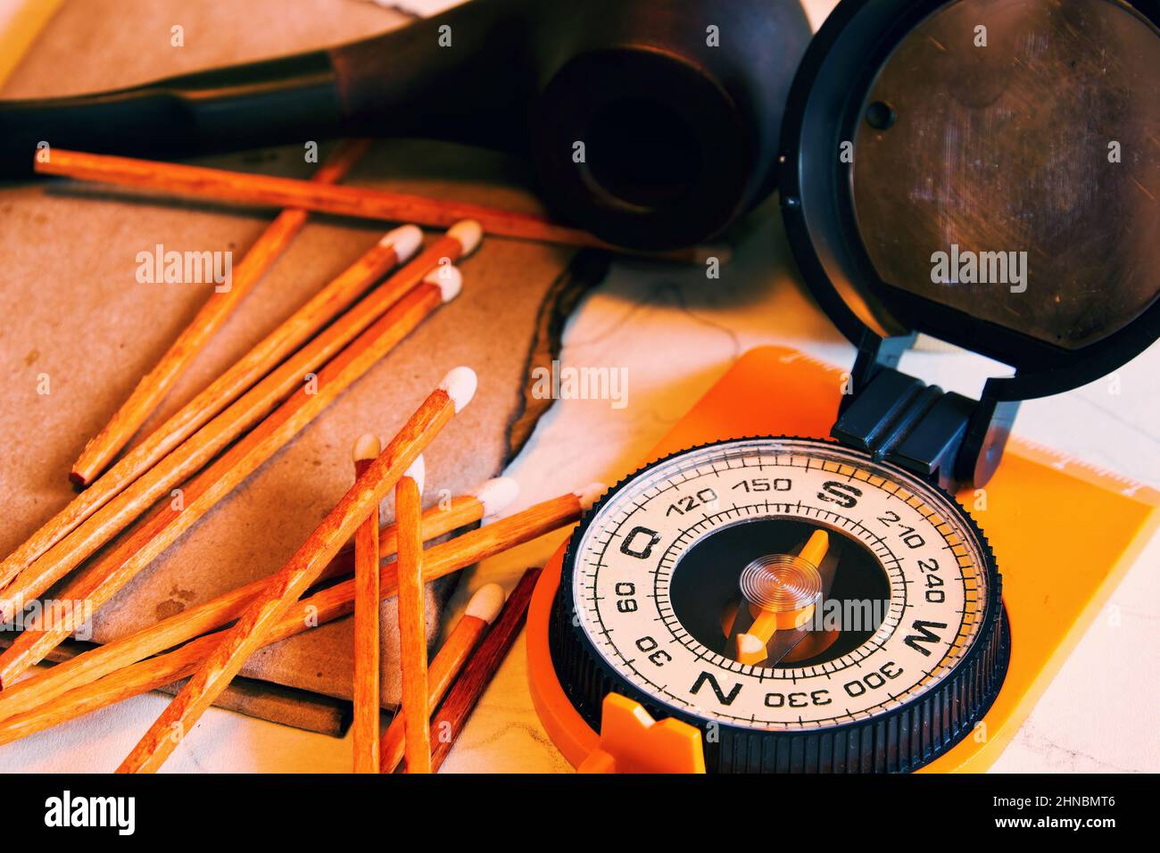 Adventurer compass, smoking pipe and matches on the burned papers ...