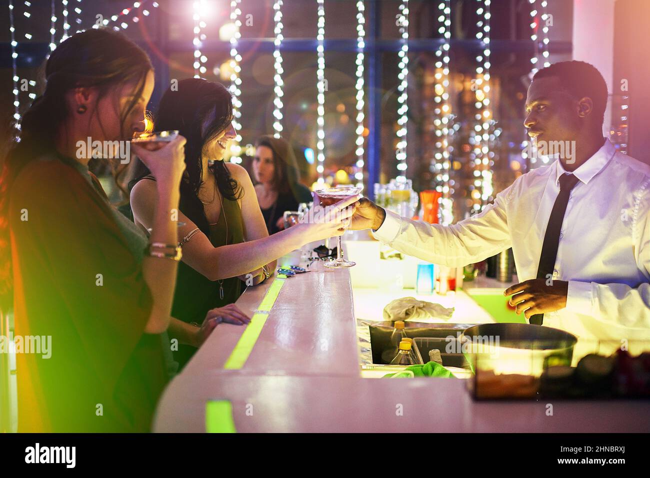 This one is on the house. Shot of a barman handing a drink to a young ...
