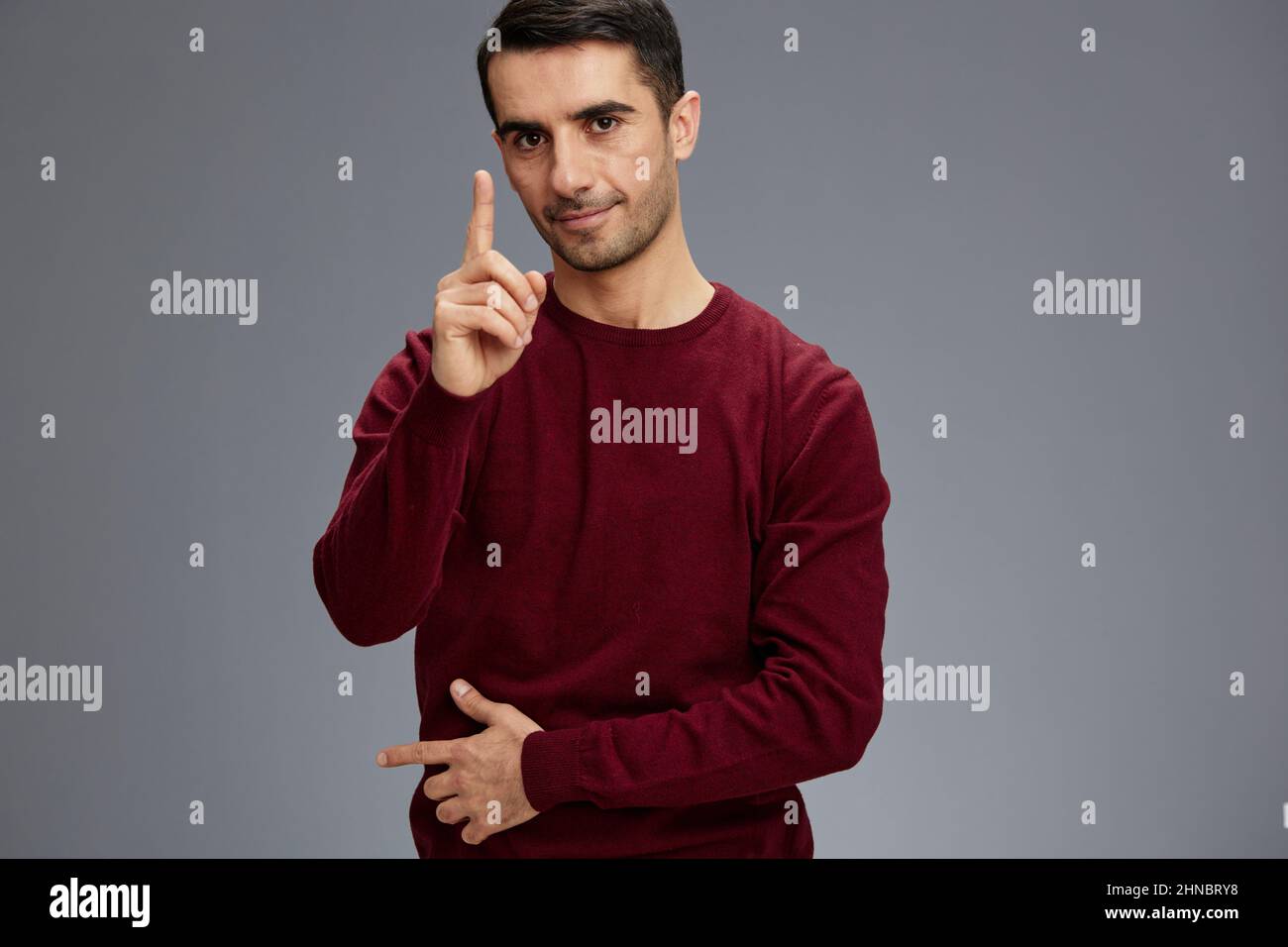 successful man holding index finger near face posing gesture with hands ...