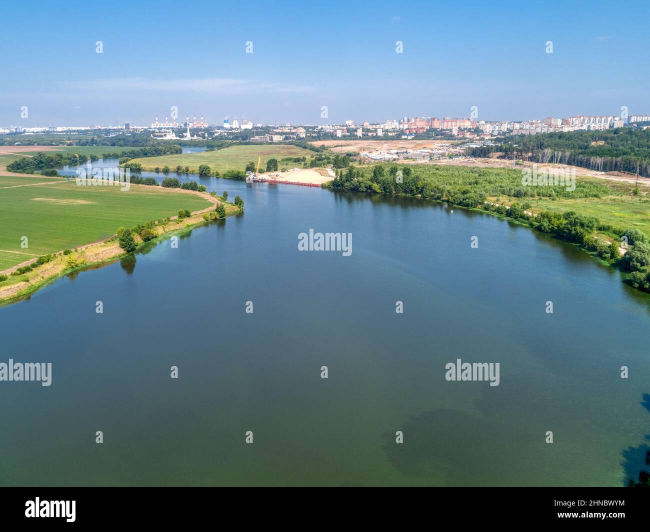 Wide river flowing between fields Stock Photo - Alamy