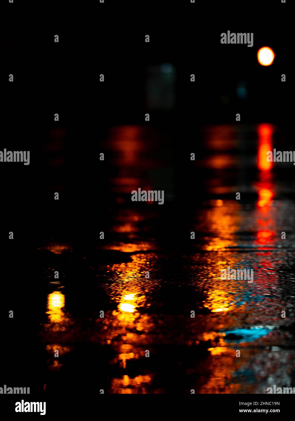 Vertical shot of the yellow lights reflected on the wet ground during ...