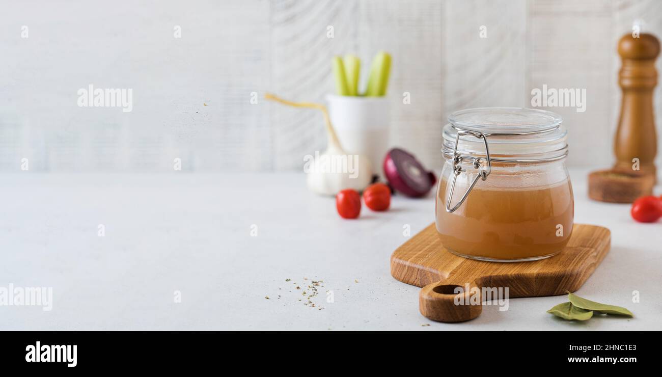 Bone broth soup in glass jar for storage on a wooden board. The concept ...