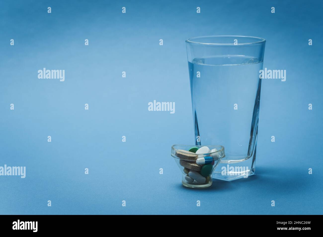 Medical concept - A glass of water and medicines on a blue background ...