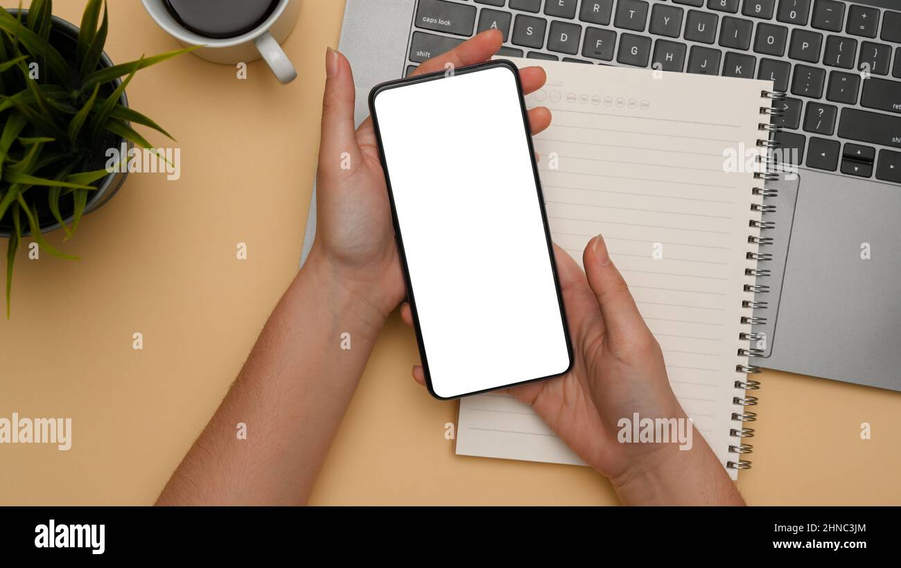 Overhead shot, A female hands holding smartphone white screen mockup ...