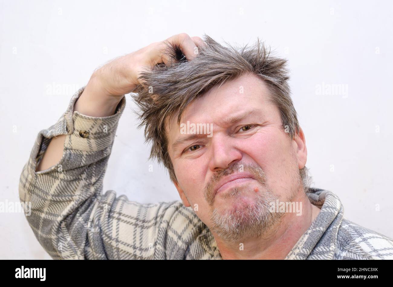 The man scratches the back of his head with his hand. A male with ...