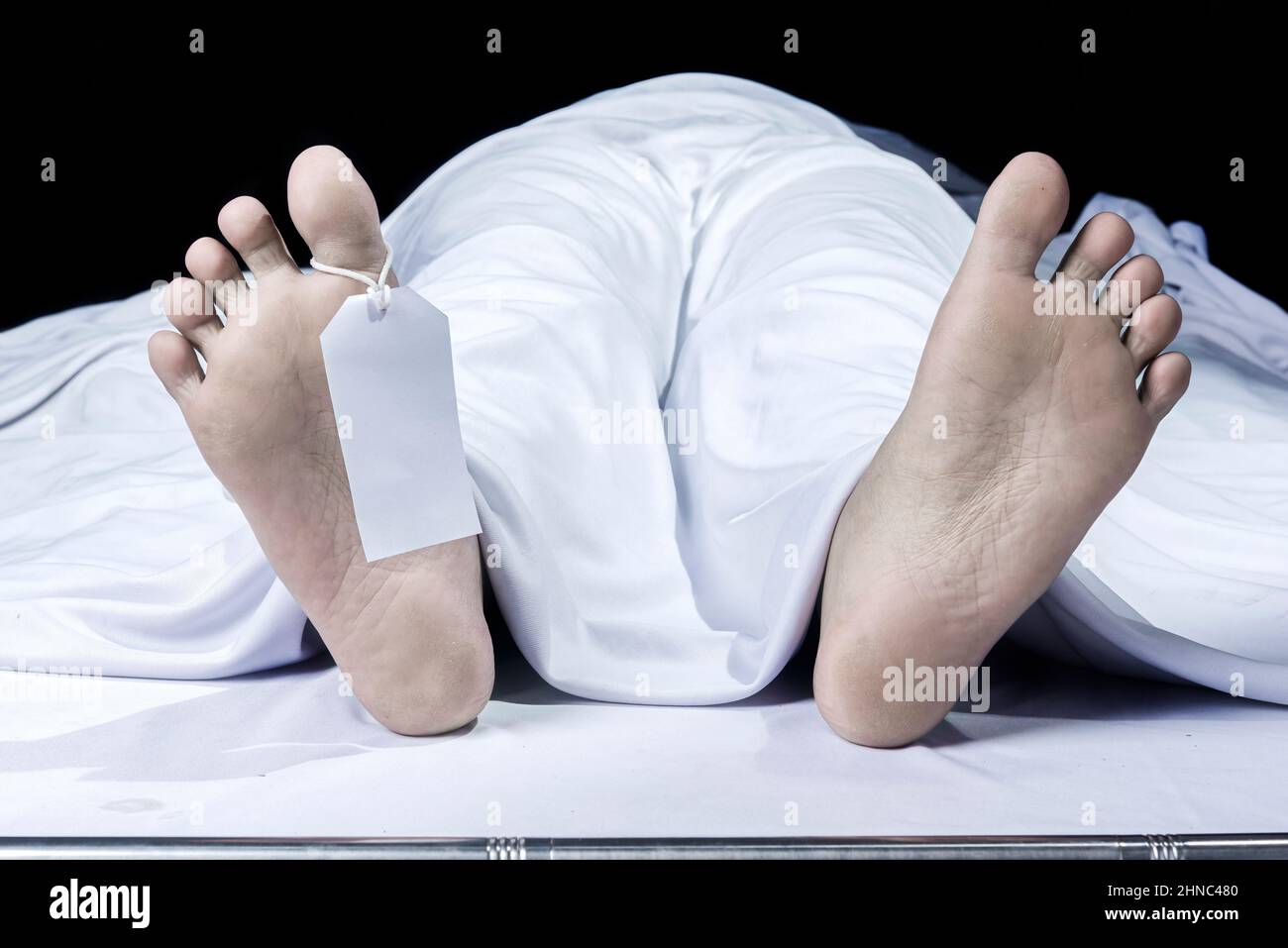 Human corpse covered with a sheet and name tag on toe in the morgue ...
