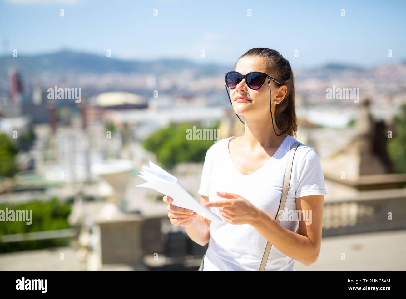 Young woman with paper guide observing sightseeings Stock Photo - Alamy