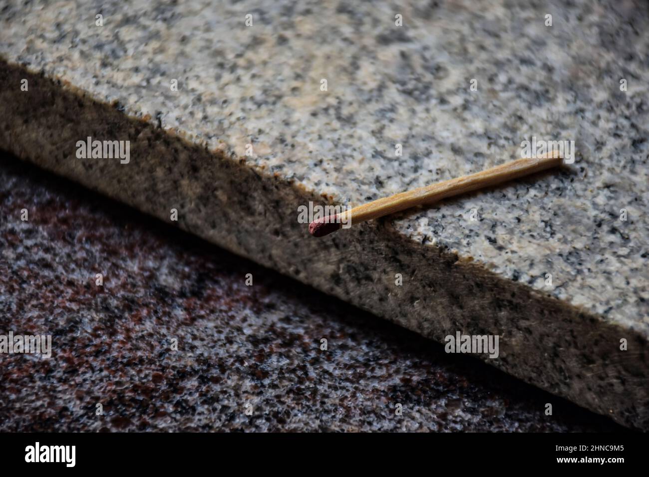 Closeup of a single matchstick kept on granite stone under natural ...