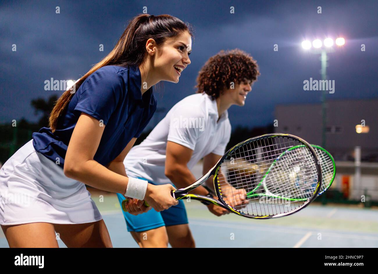 Beautiful young people are playing tennis as a team on tennis court ...