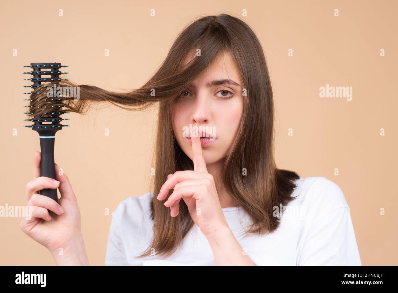 Young woman hairdresser with comb brushing hair. Brunette woman combing ...