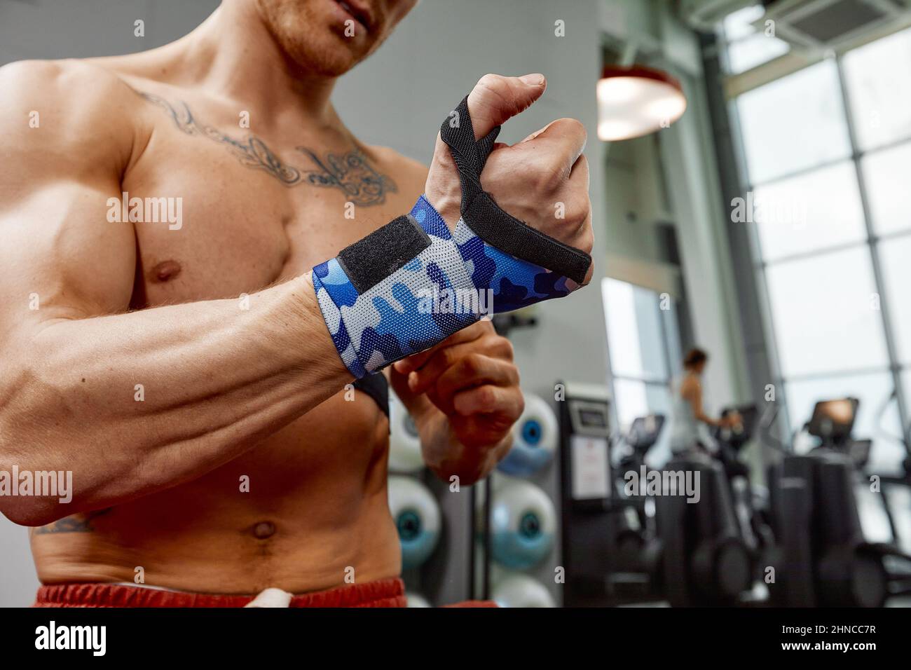 A beautiful athlete boxer, wraps his hands on sports bandages for ...
