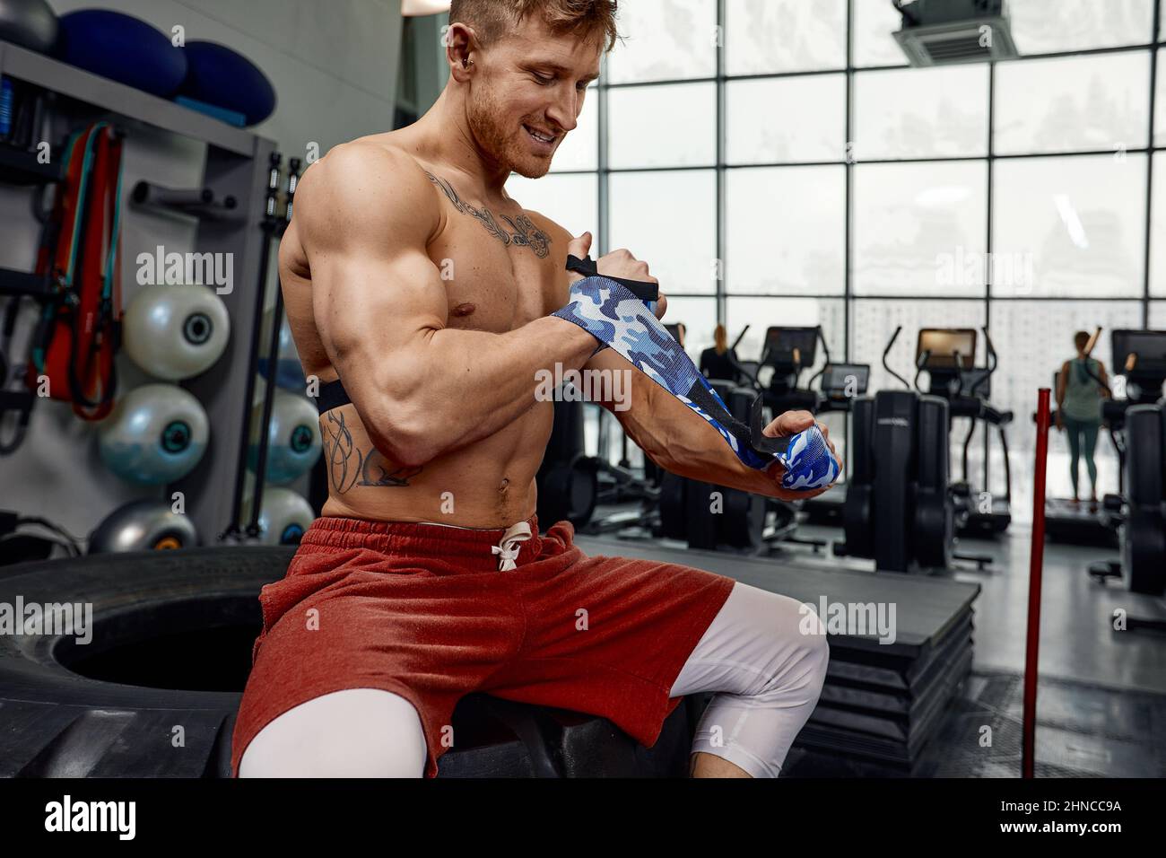 A beautiful athlete boxer, wraps his hands on sports bandages for ...