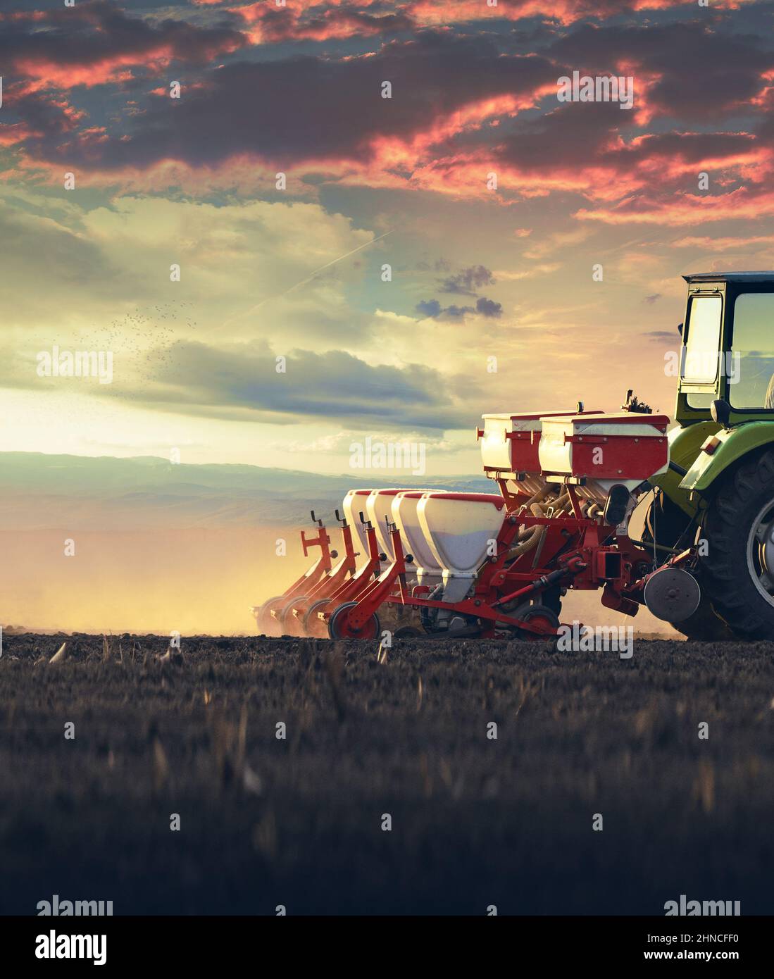 Farmer with tractor seeding - sowing crops at agricultural field ...