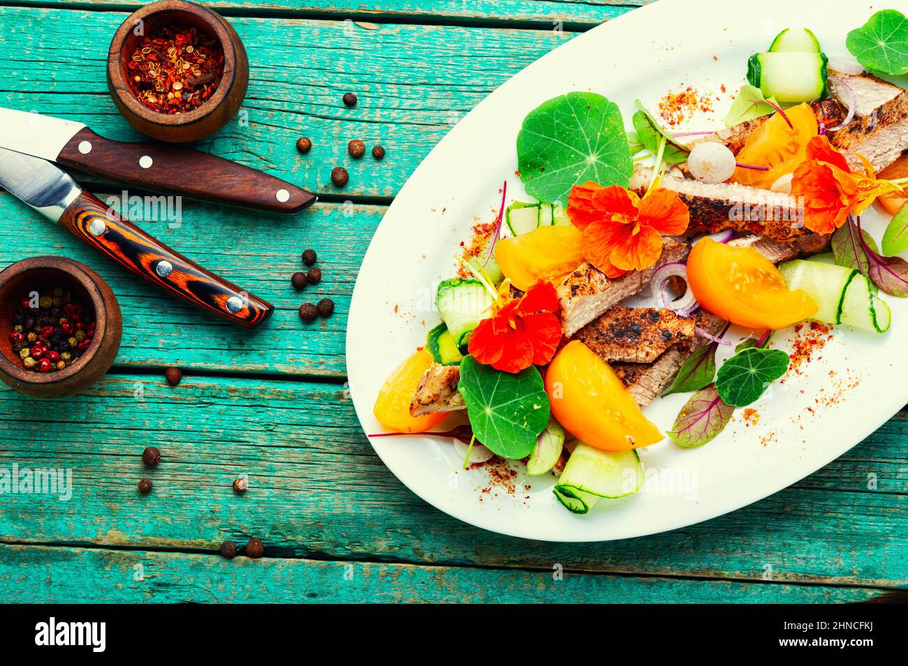 Meat steak decorated with nasturtium flowers. Sliced pork steak, salad ...