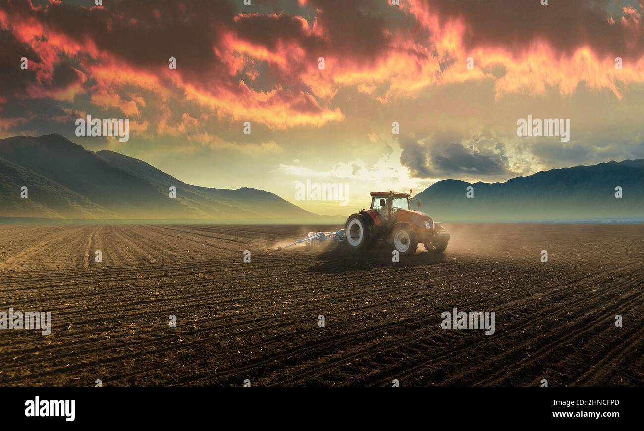 Farmer with tractor seeding - sowing crops at agricultural field ...