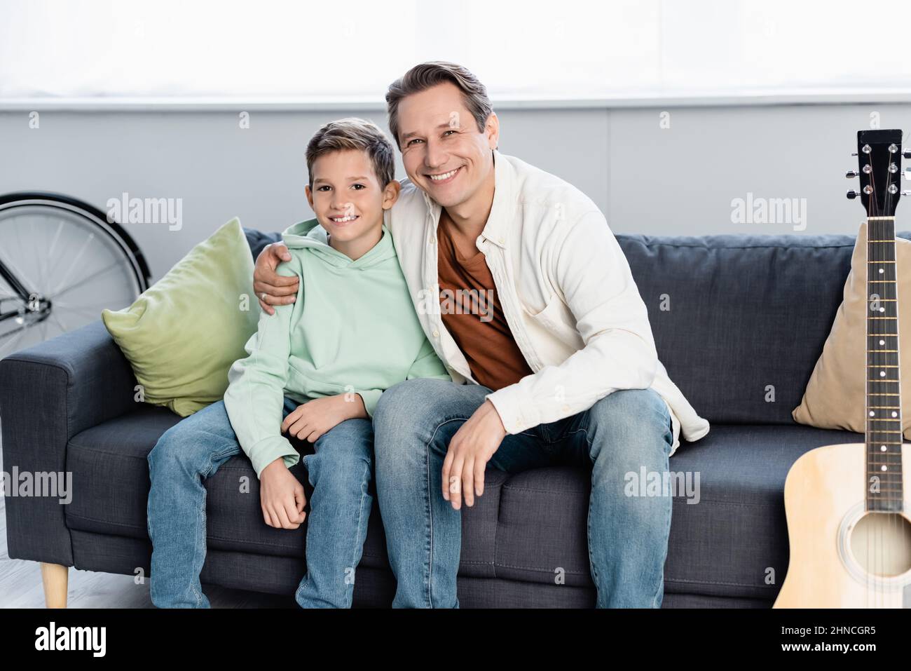 Father hugging preteen boy near acoustic guitar in living room Stock ...