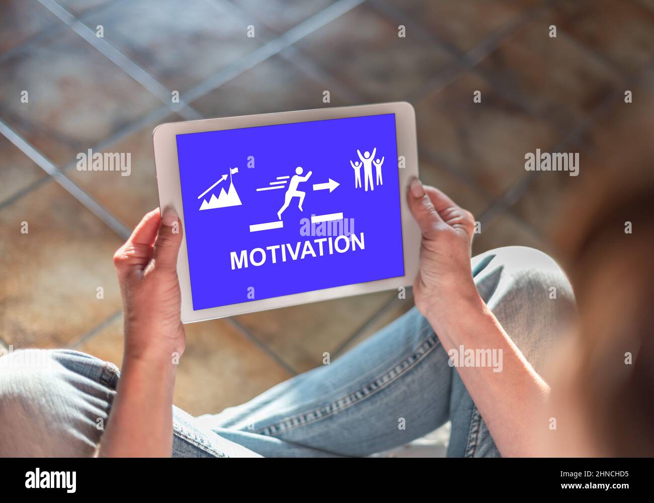 Woman sitting on the floor with a tablet showing motivation concept ...