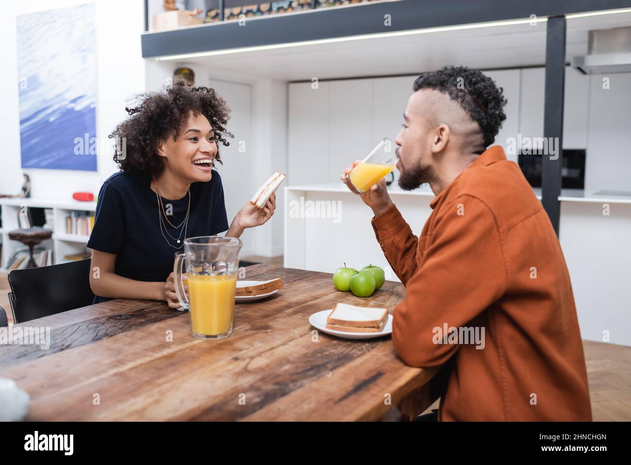 cheerful african american woman holding sandwich while having lunch ...