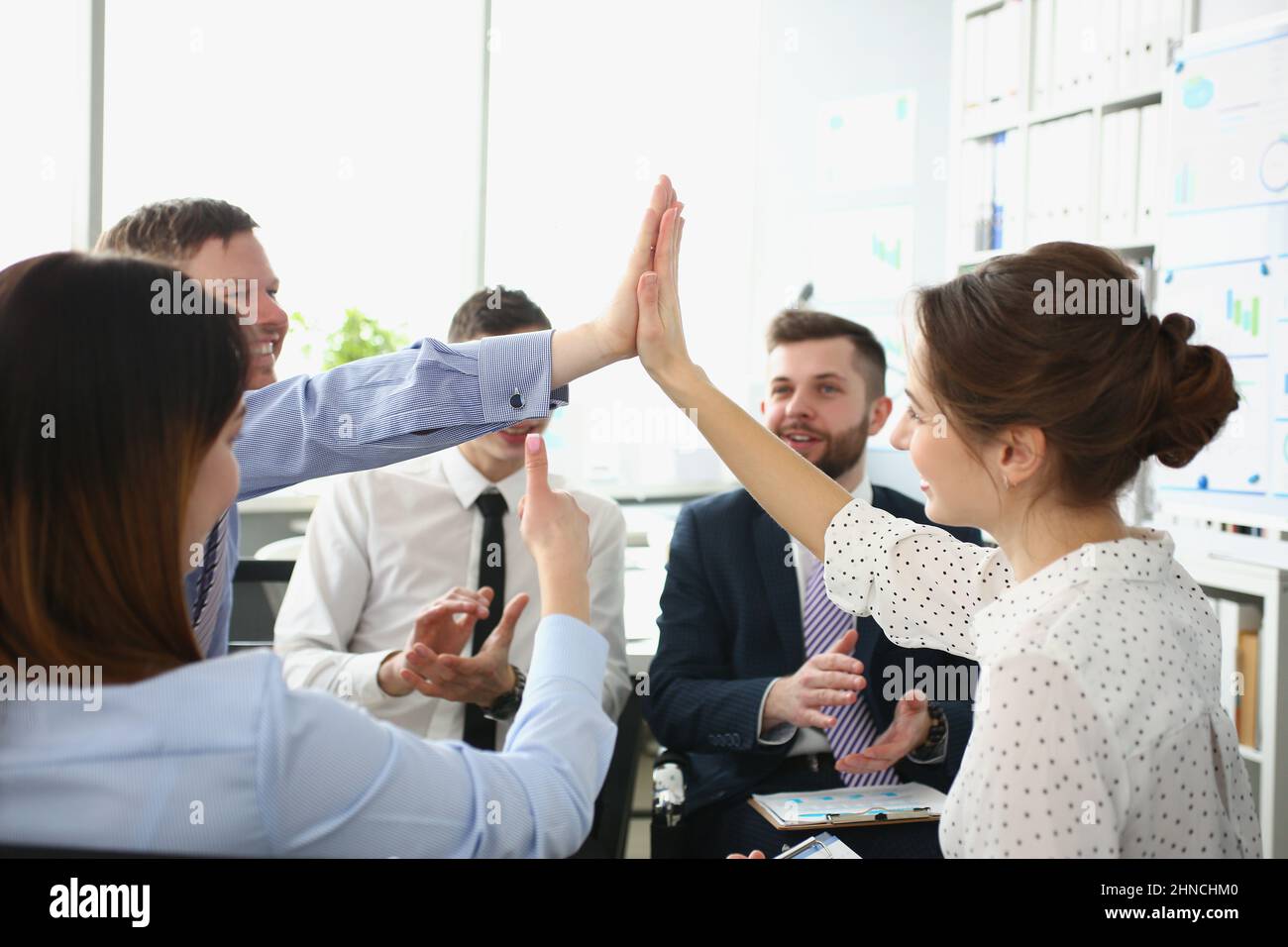 Colleagues give high five gesture in order to celebrate end of company ...