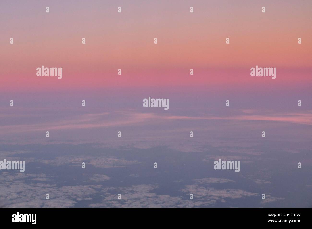 Pink sunset above the clouds as seen from inside an Airbus A320 at ...