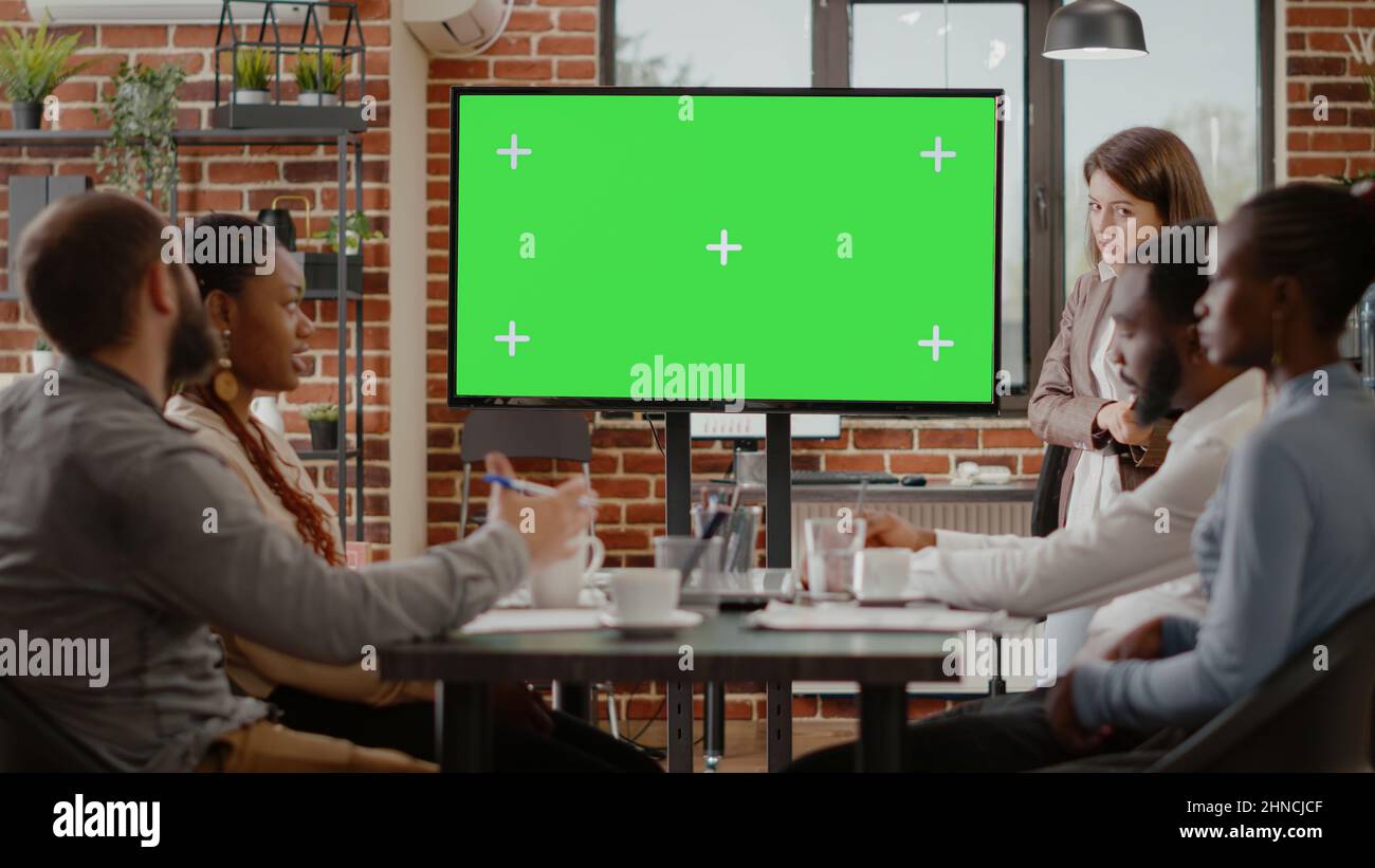 Workmates using isolated green screen on monitor at business meeting in ...