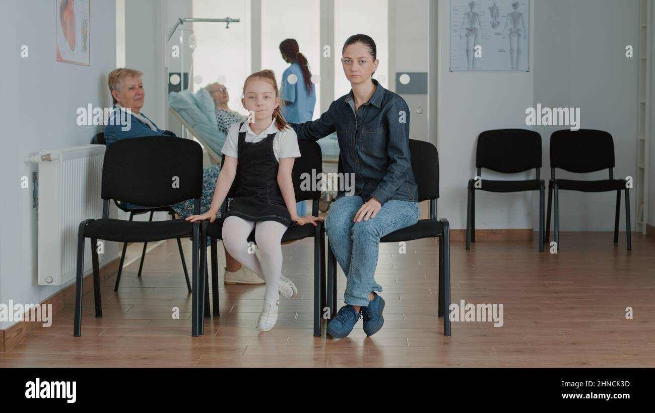 Portrait of mother and little girl in waiting room at clinic. Woman ...