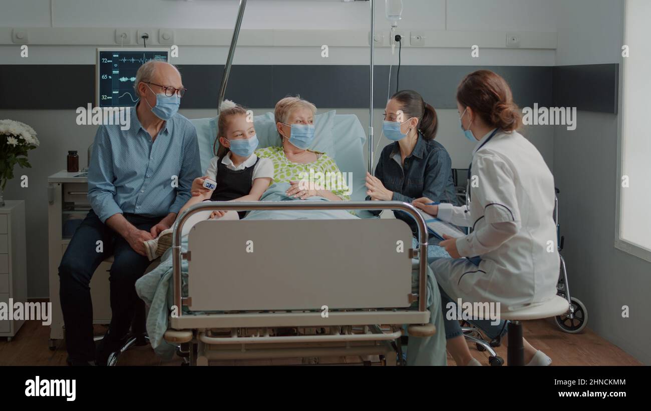Doctor discussing about treatment with ill patient at visit with family ...
