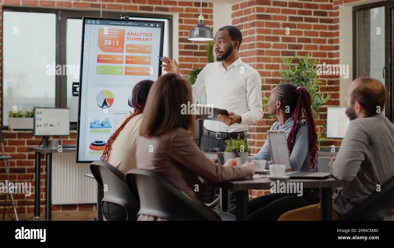 Company employee presenting business strategy with charts on monitor ...