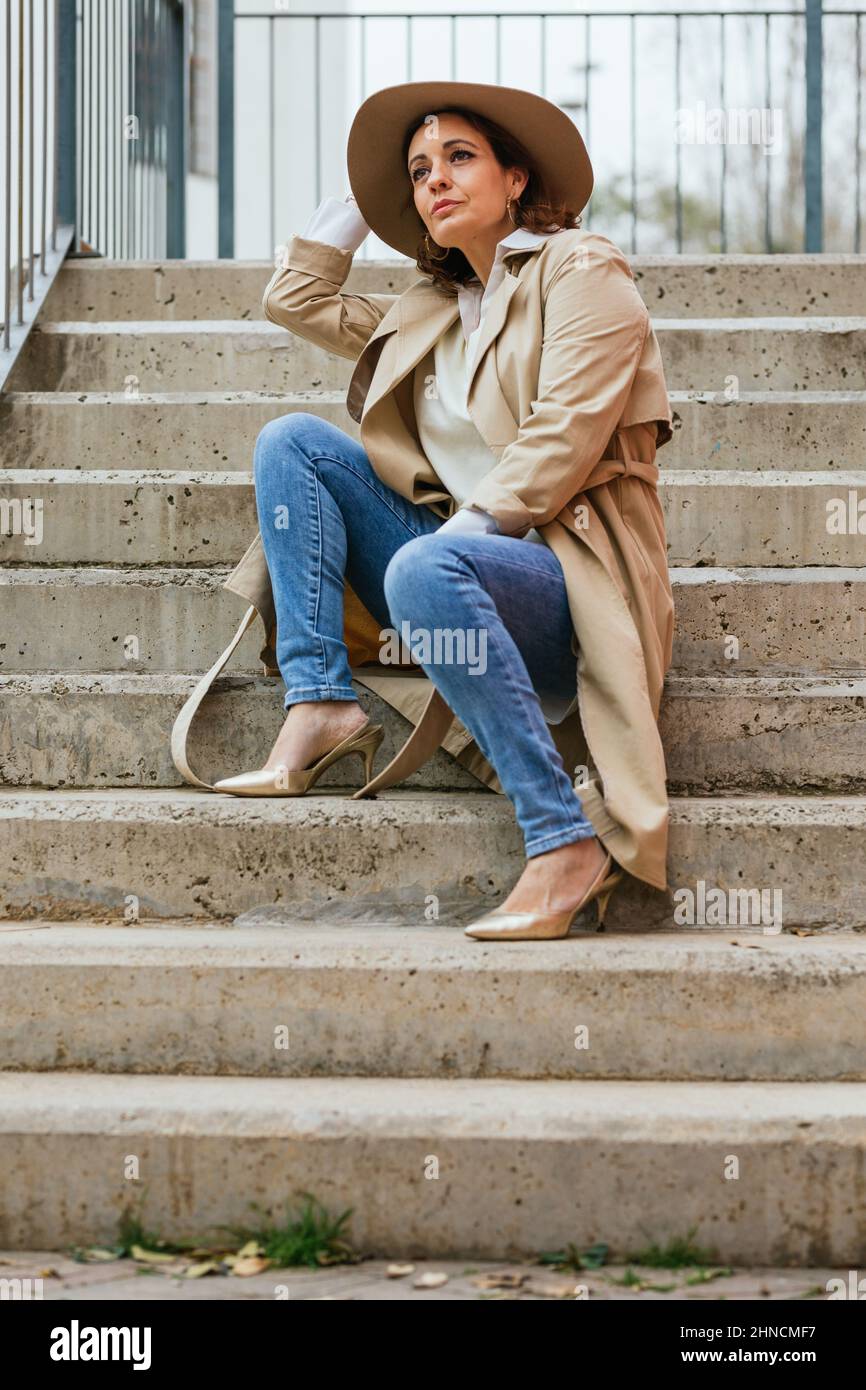 Thoughtful woman thinking about something while sitting on the stairs ...