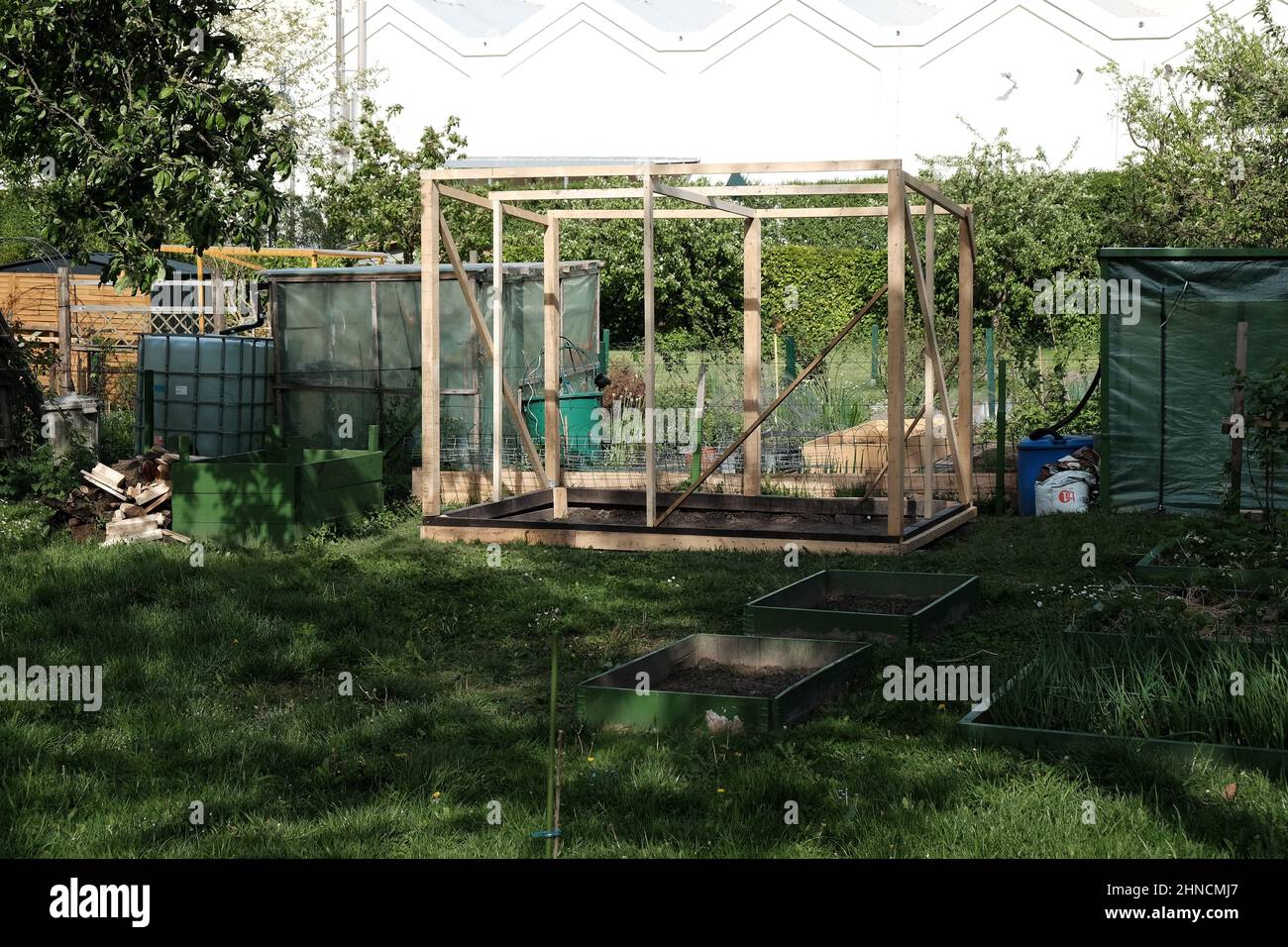 View of a green garden with different plants and frame for a gazebo ...