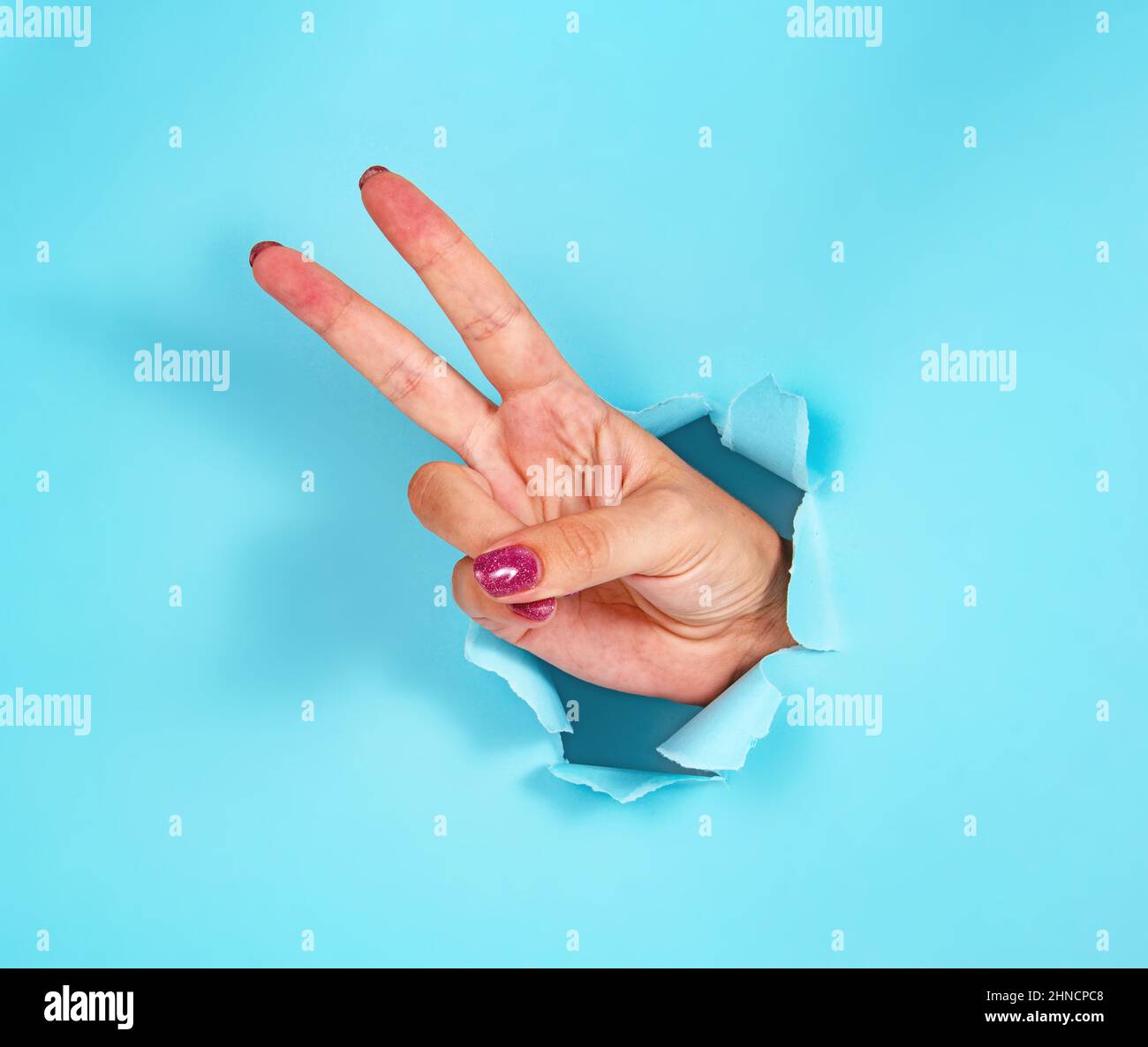 Woman hand two fingers in whole of torn blue paper background Stock ...