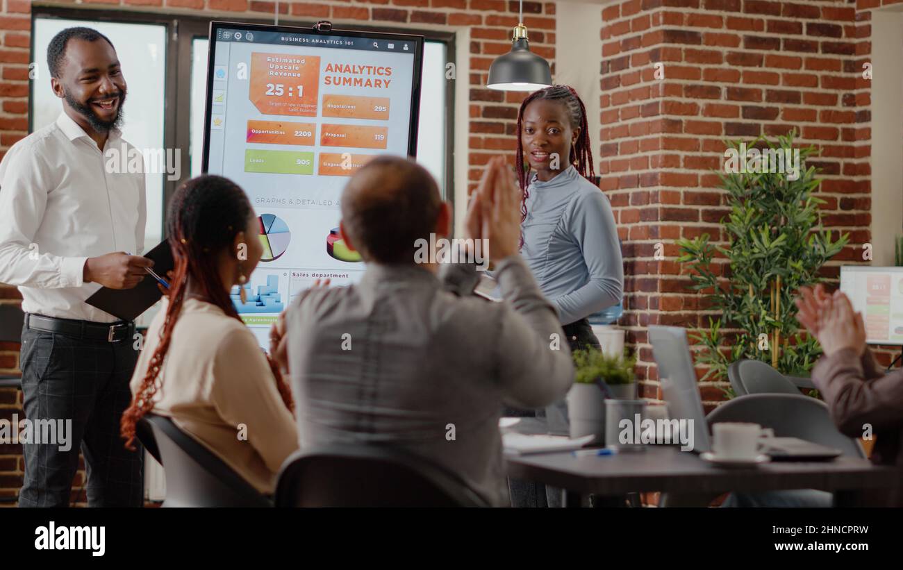 Workmates clapping hands and celebrating accomplishment with project ...