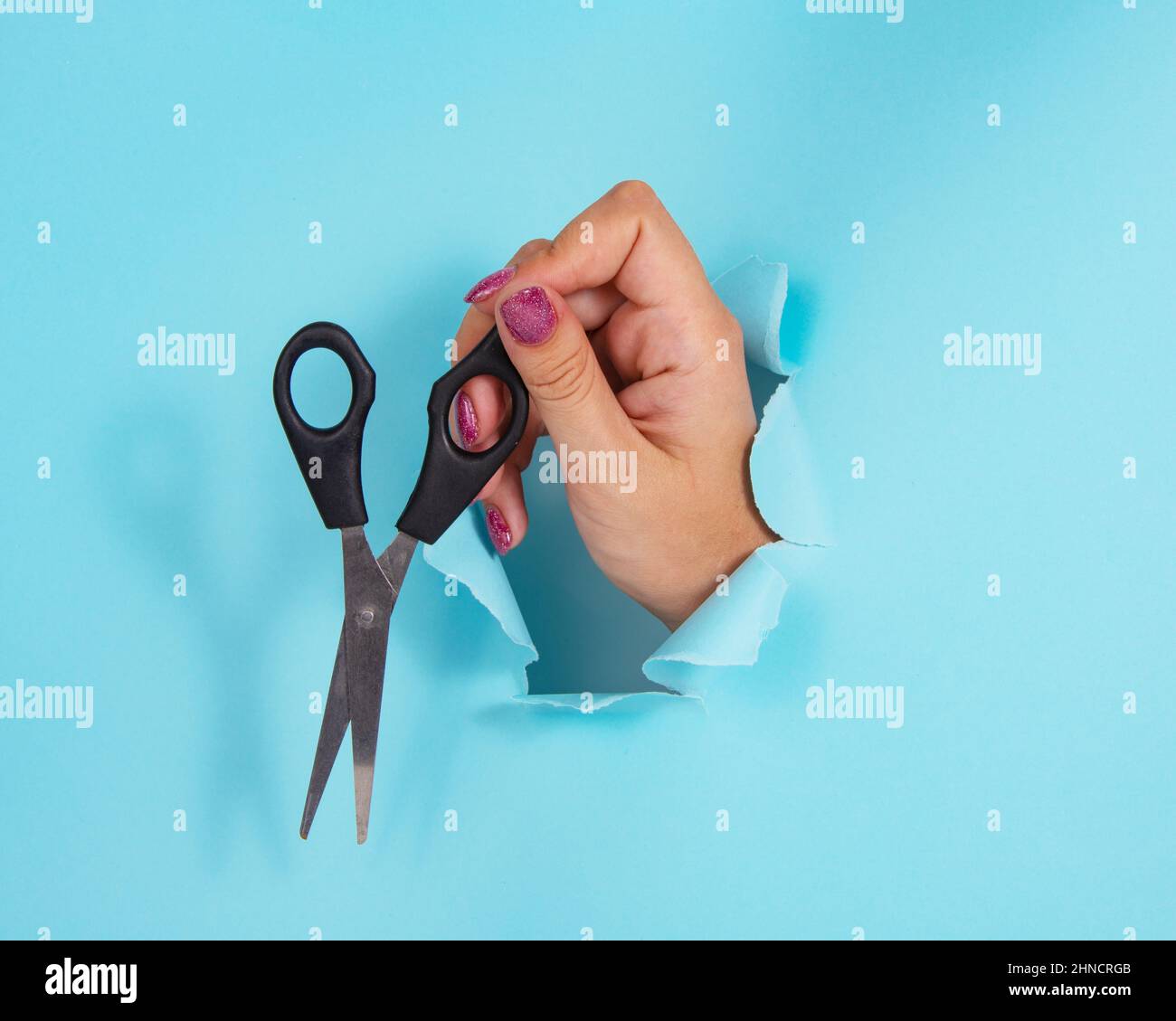 Woman hand with scissors in whole of torn blue paper background Stock ...