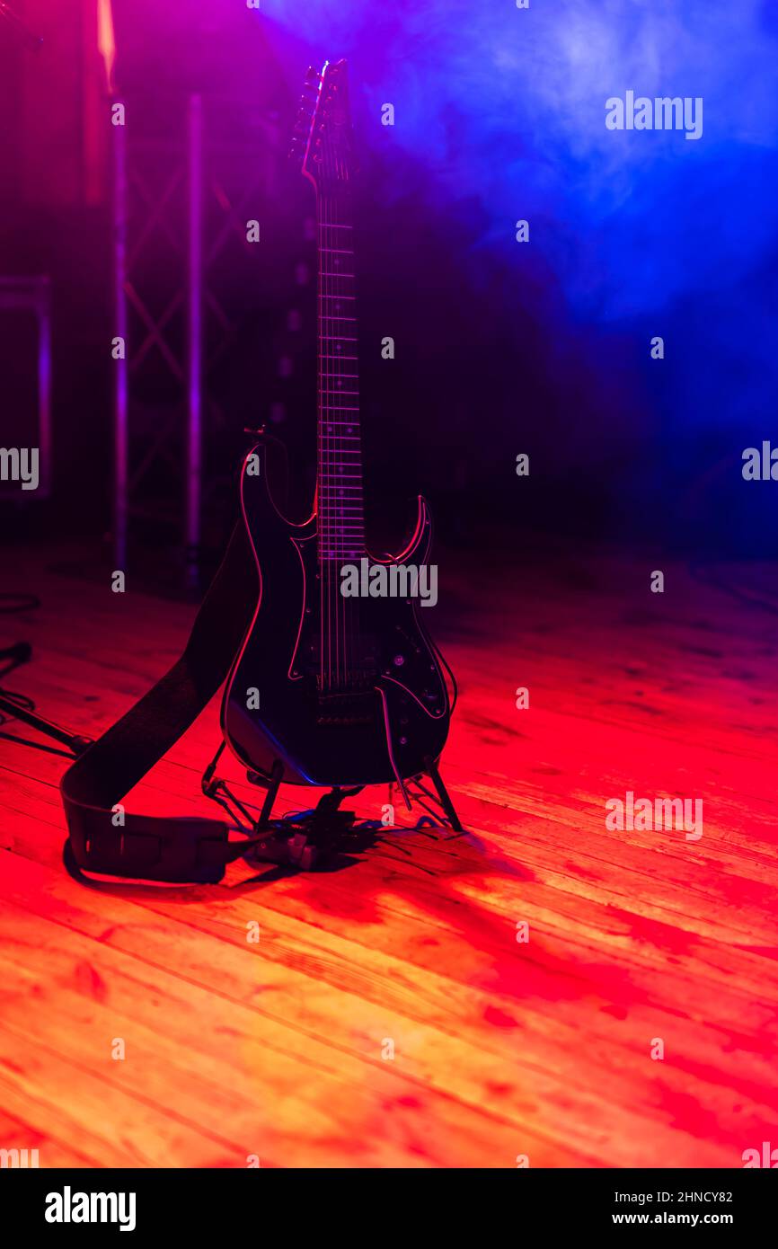 A black electric guitar based on a stand placed on the stage. Subject ...